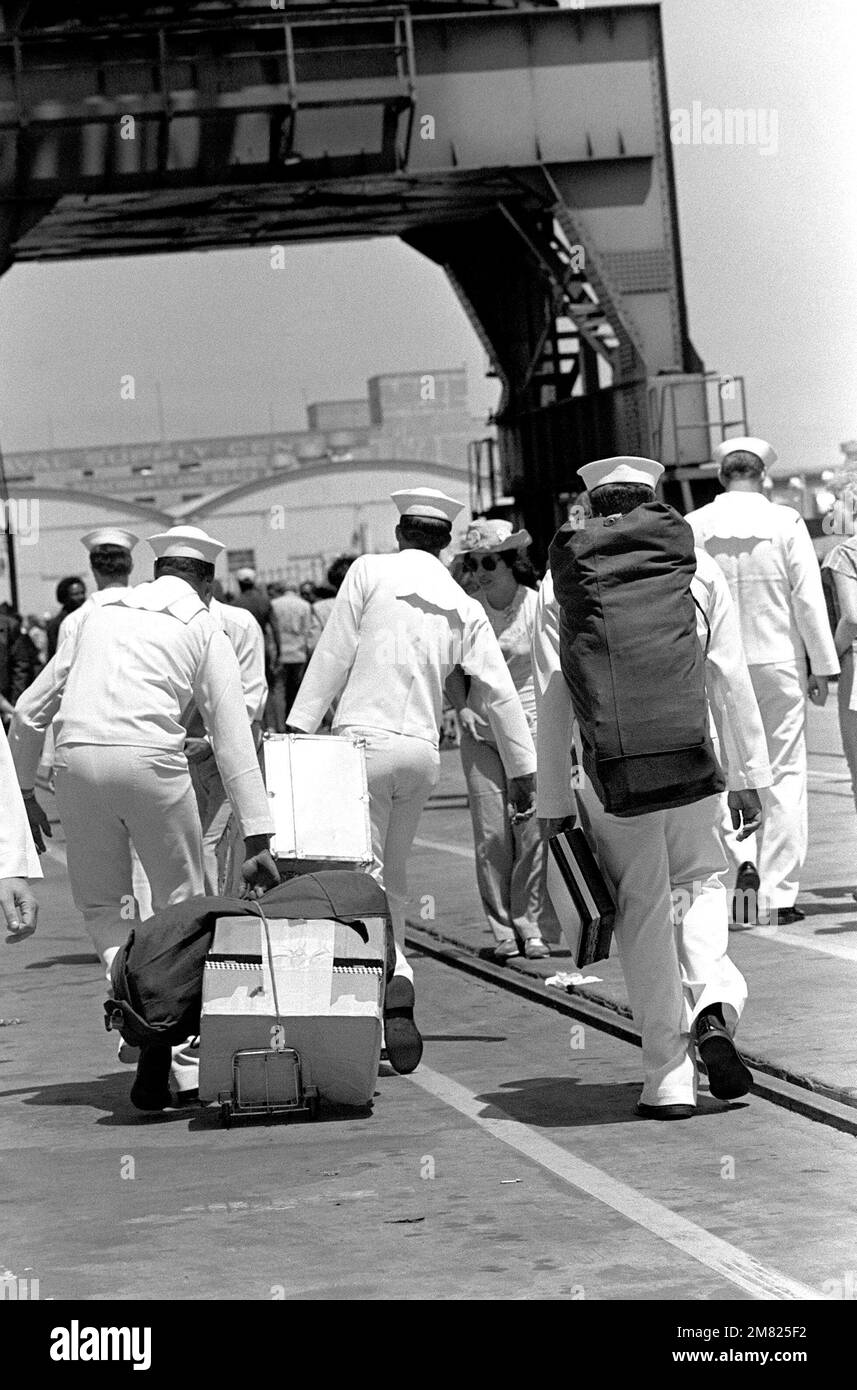 Crew members carry their gear off the dock upon returning to home port ...