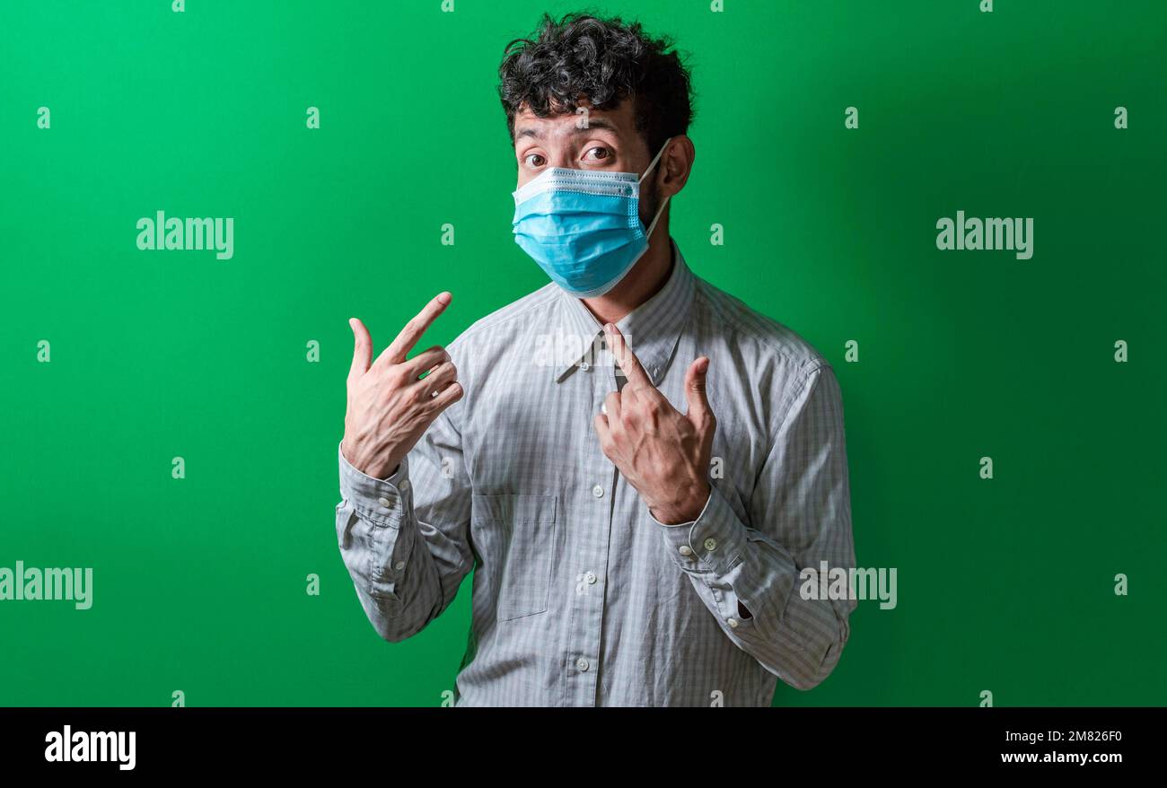 Isolated man wearing double surgical mask pointing to them with thumbs ...
