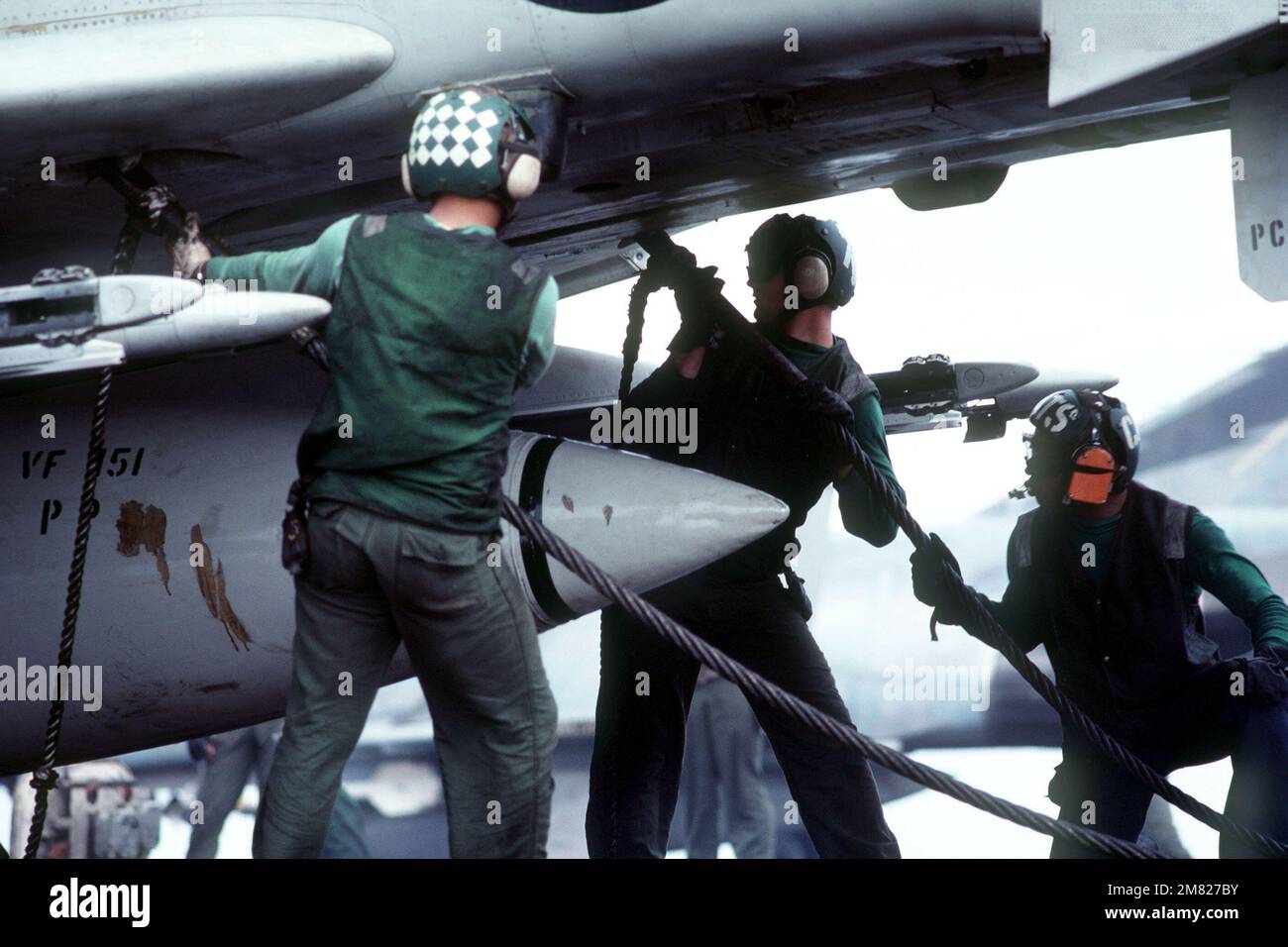 Crewman attach a launching bridle to an F-4 Phantom II aircraft from ...