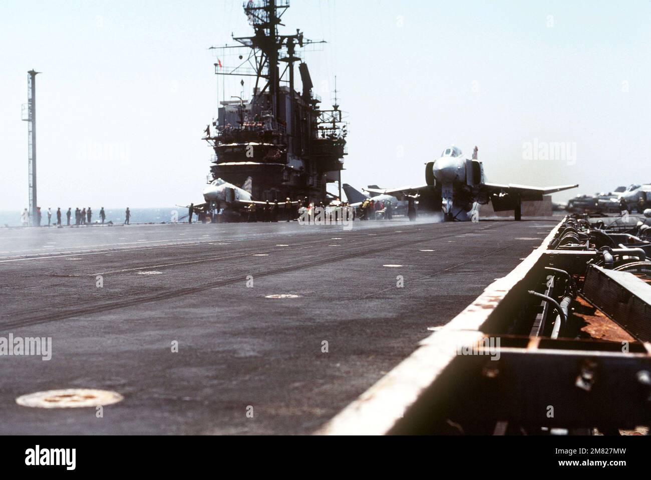 Two F-4 Phantom II aircraft are prepared for takeoff on the flight deck ...