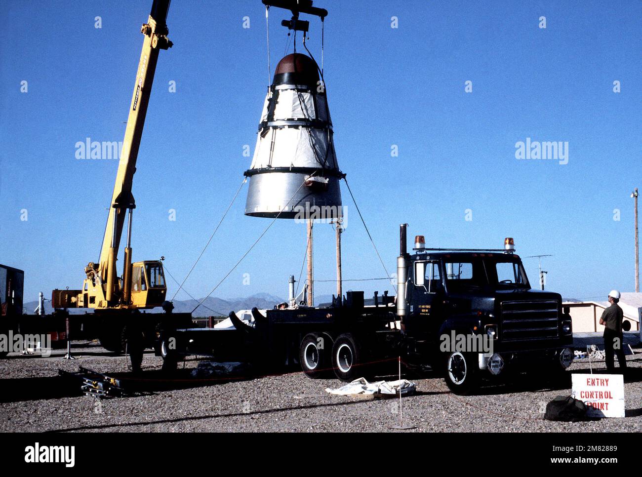 A Titan II reentry vehicle is lowered by crane onto a trailer after its ...