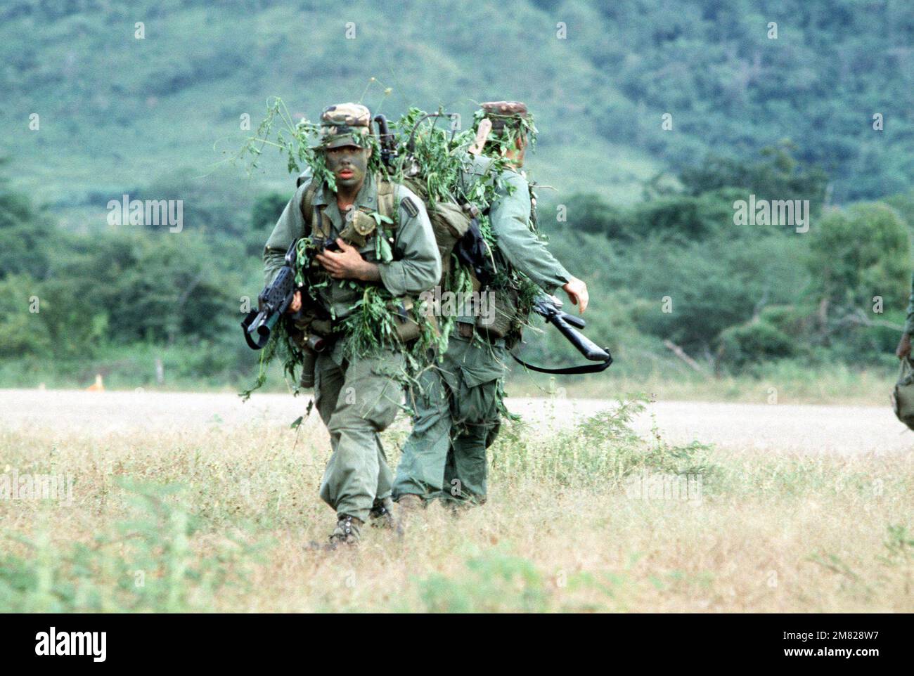 Two soldiers wearing camouflage, armed with an M16A1 rifles ...