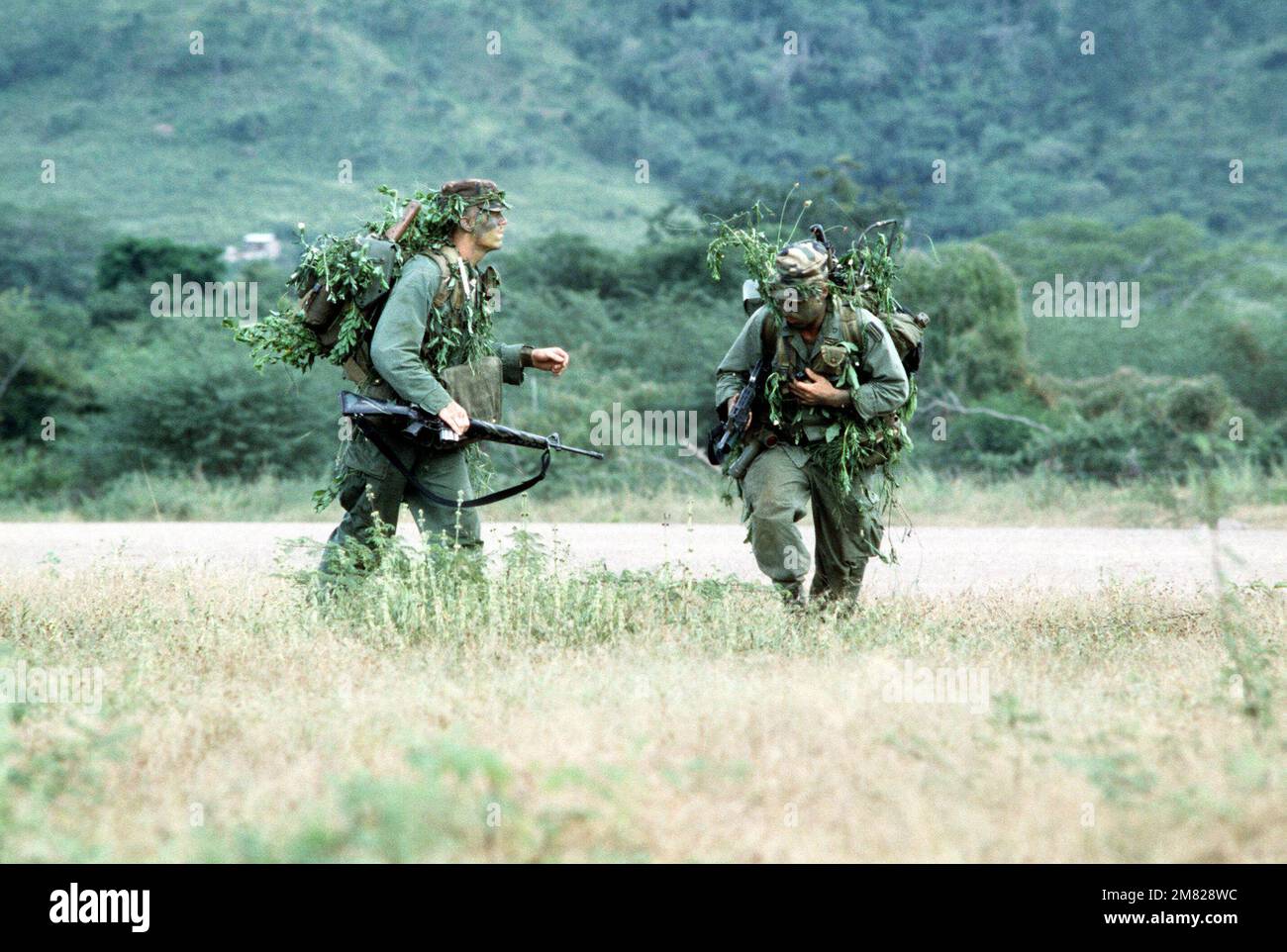 Two soldiers wearing camouflage, armed with an M16A1 rifles ...