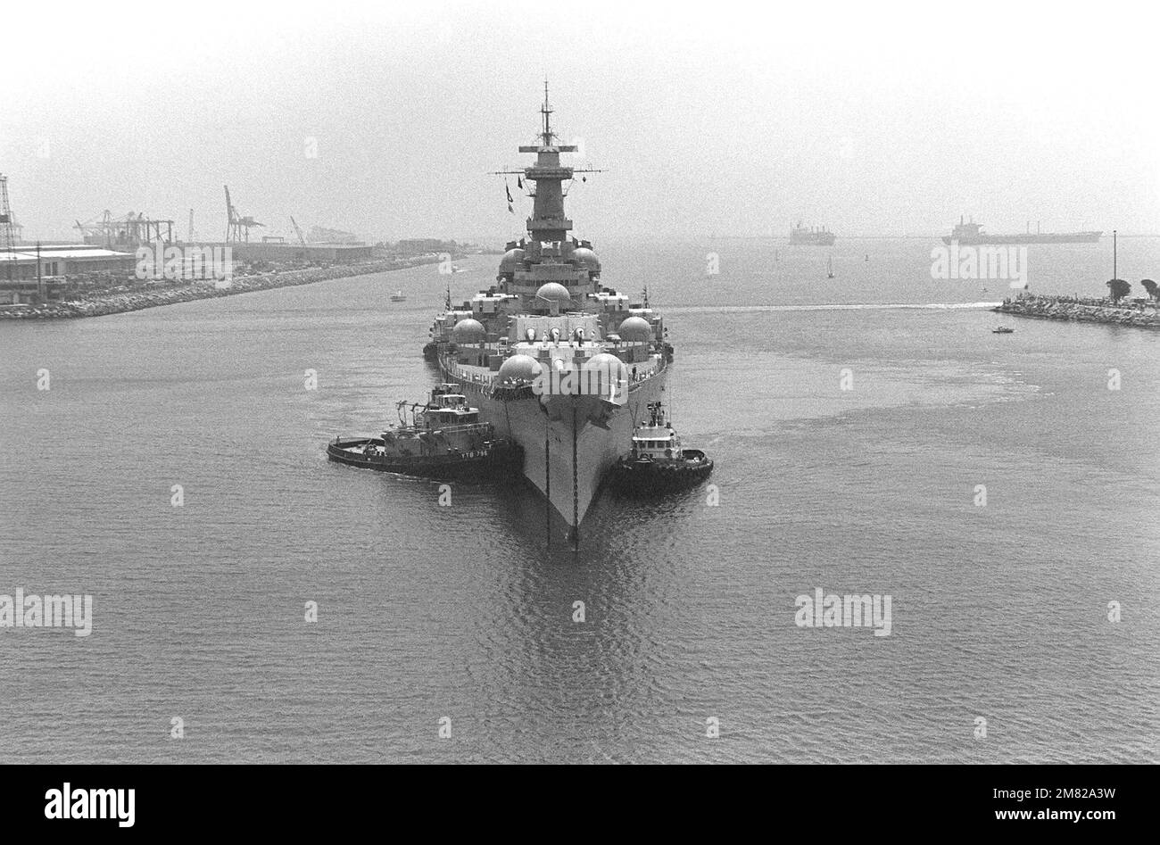 The large harbor tug USS SACO (YTB 796) and several commerical tugs tow ...