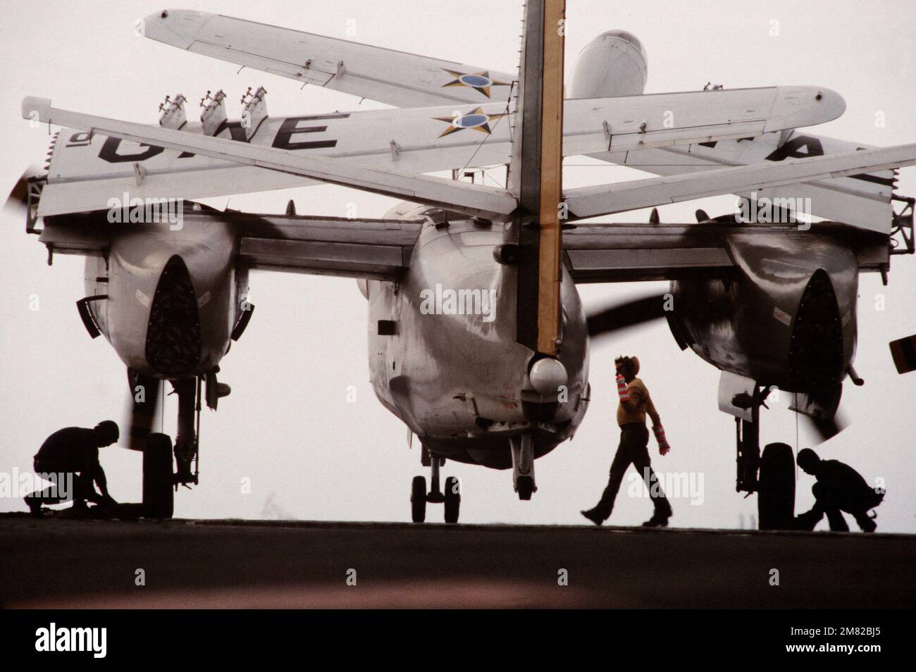 Flight deck crewmen remove chocks from the main landing gear of an S-2E ...