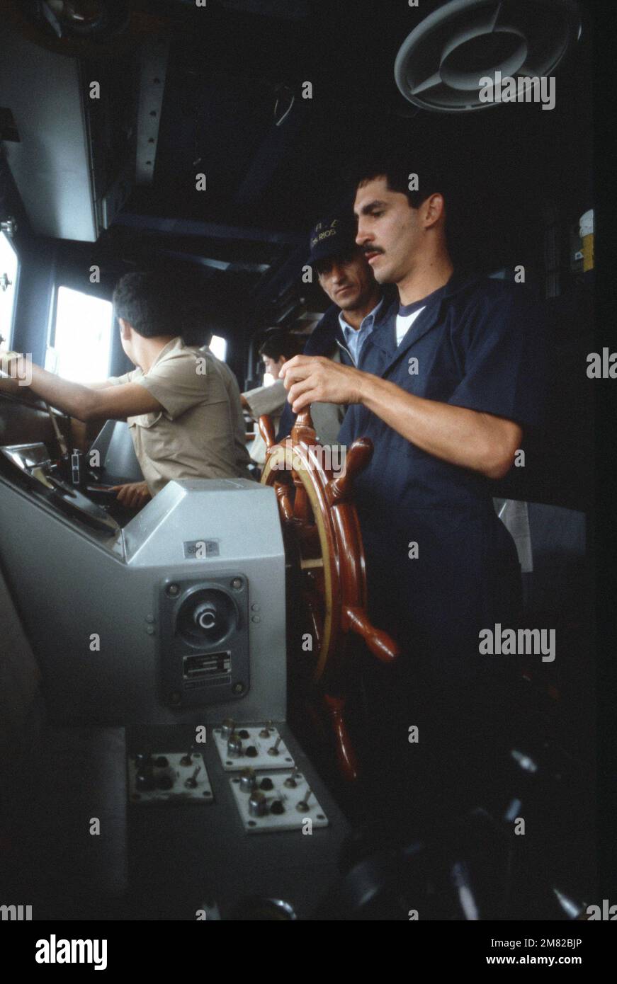 US Navy Radioman 2nd Class (RM2) Jesus Cordero mans the helm aboard the ...