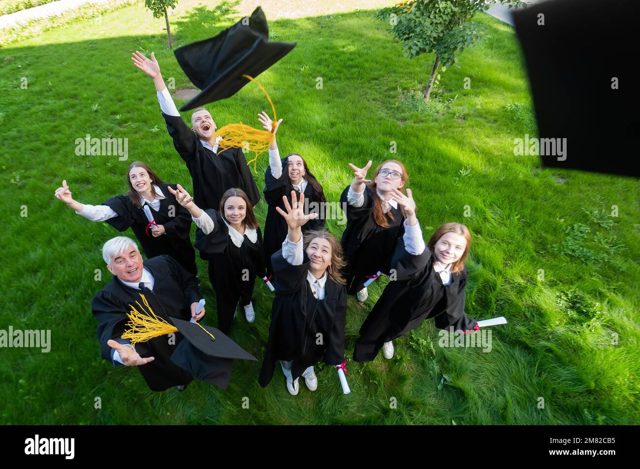 Classmates in graduation gowns throw their caps. View from above Stock ...