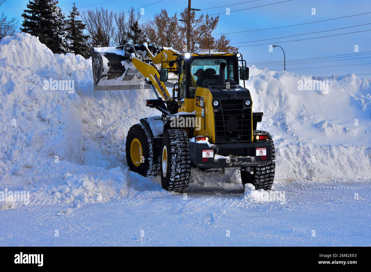 Front end loader works to pile up large amount of snow in mall parking ...