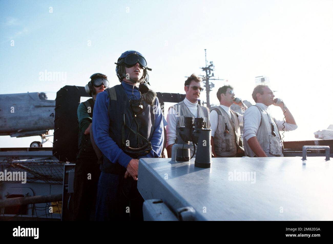 The landing signal officer directs an incoming plane as observers watch ...