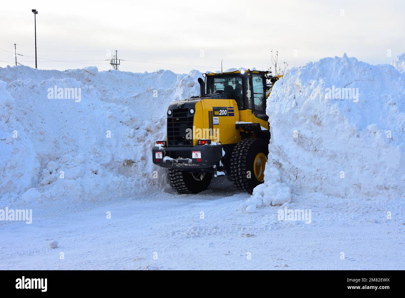 Front end loader works to pile up large amount of snow in mall parking ...