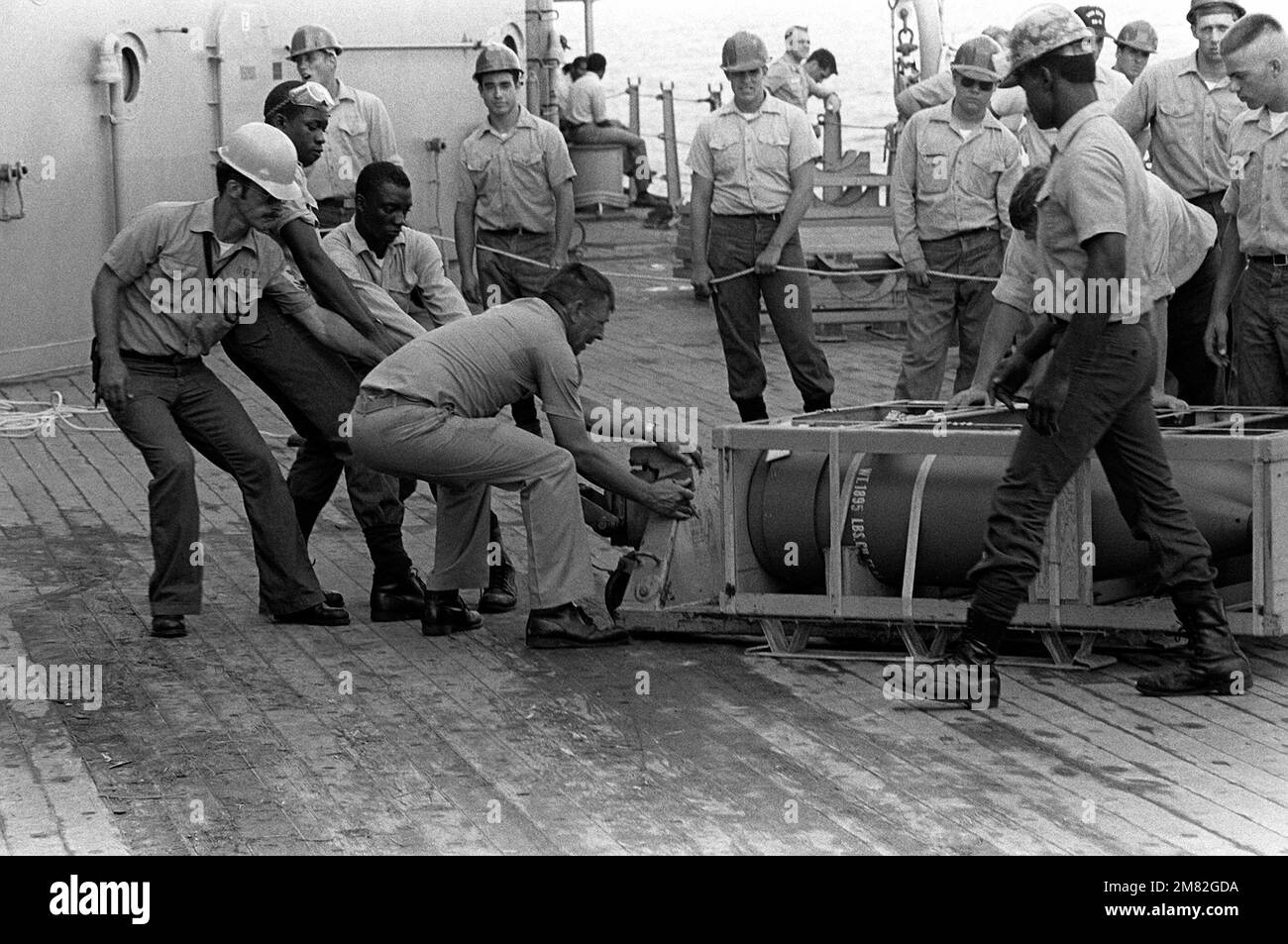 Crewmen haul a pallet of 16-inch projectiles across the deck of the ...