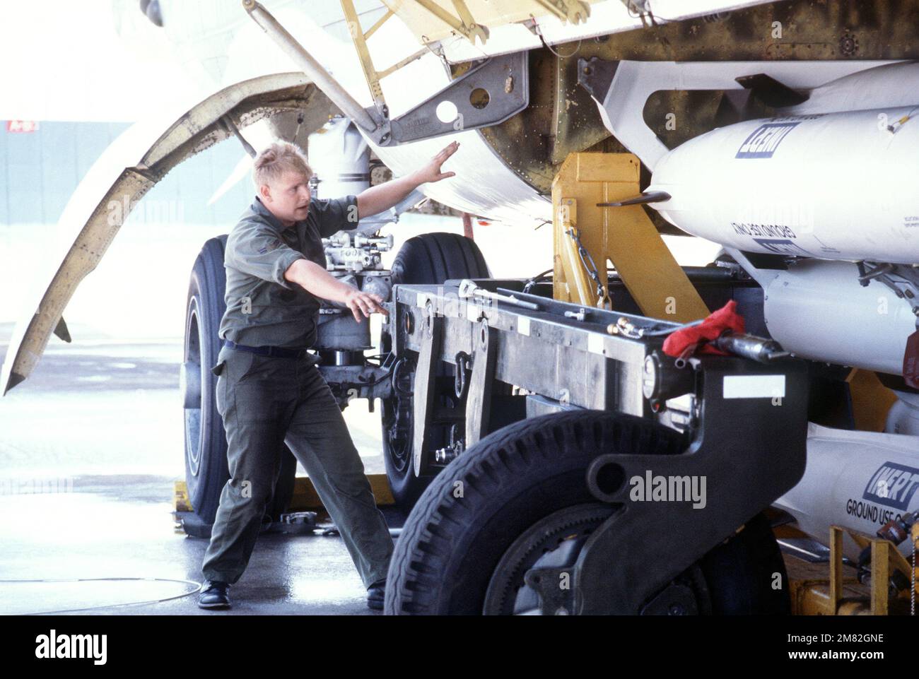 A member of the 410th Munitions Maintenance Squadron guides a bomb ...