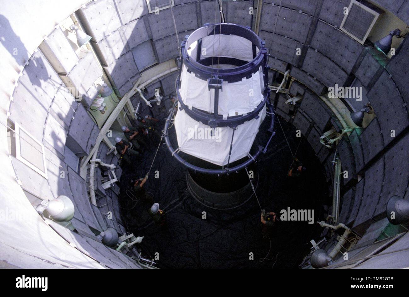 A reentry vehicle collar is lowered into a silo as members of the 381st ...