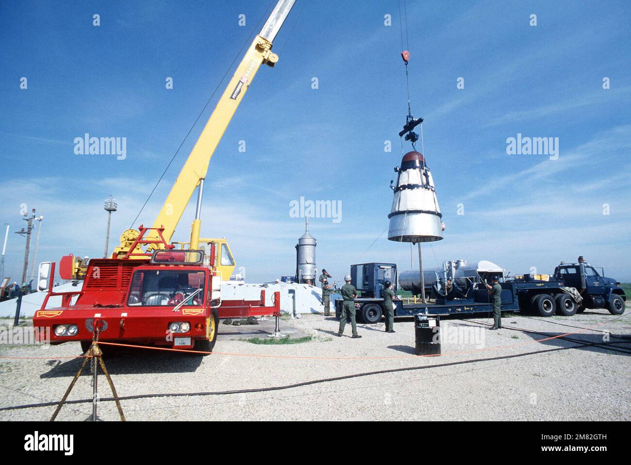 A Titan II reentry vehicle is lowered by crane onto a trailer for ...