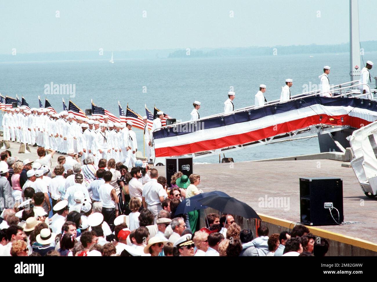 Guests look on as crewmen go aboard the Aegis guided missile cruiser ...