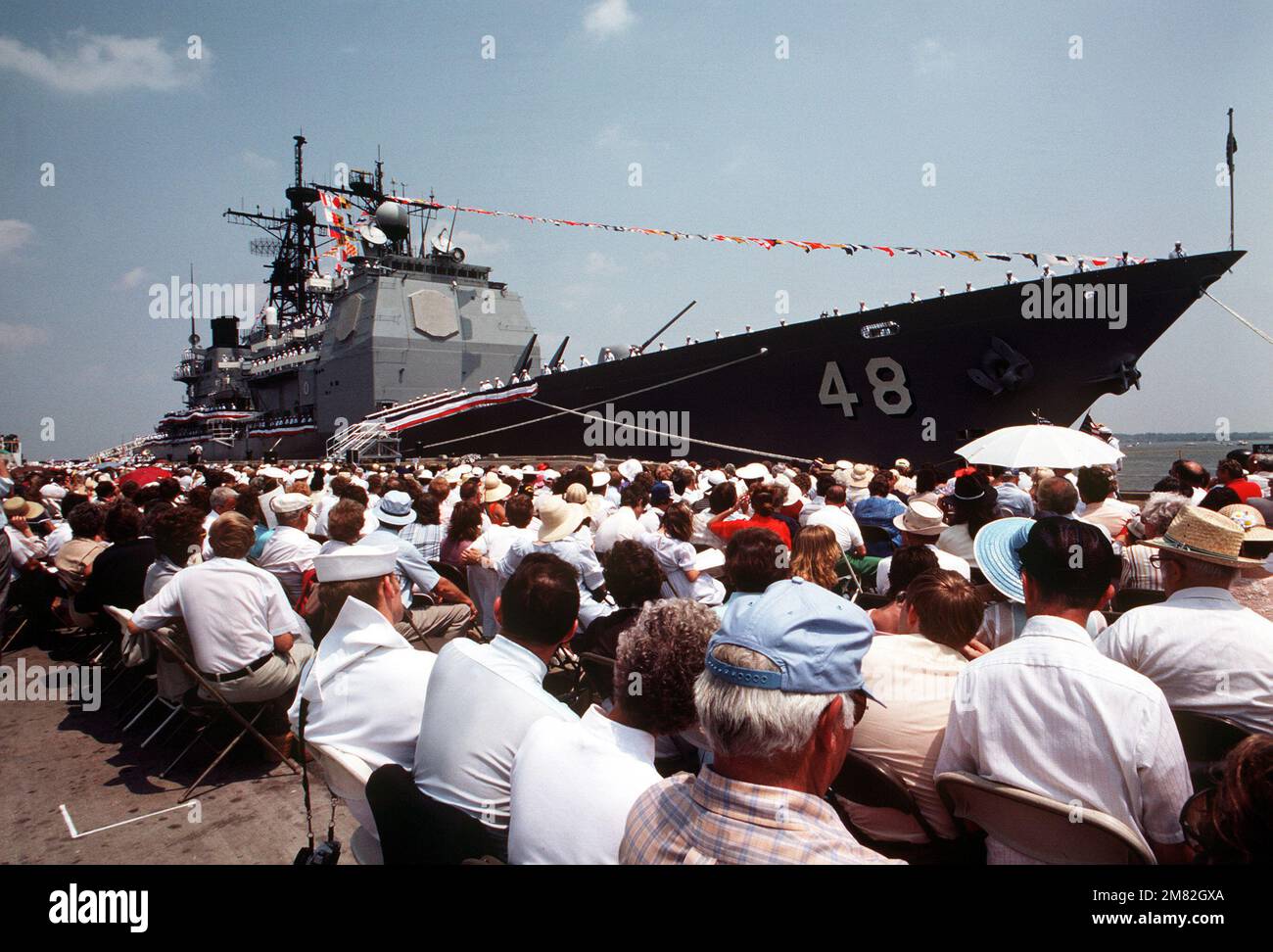 Guests look on as the crew of the Aegis guided missile cruiser USS ...