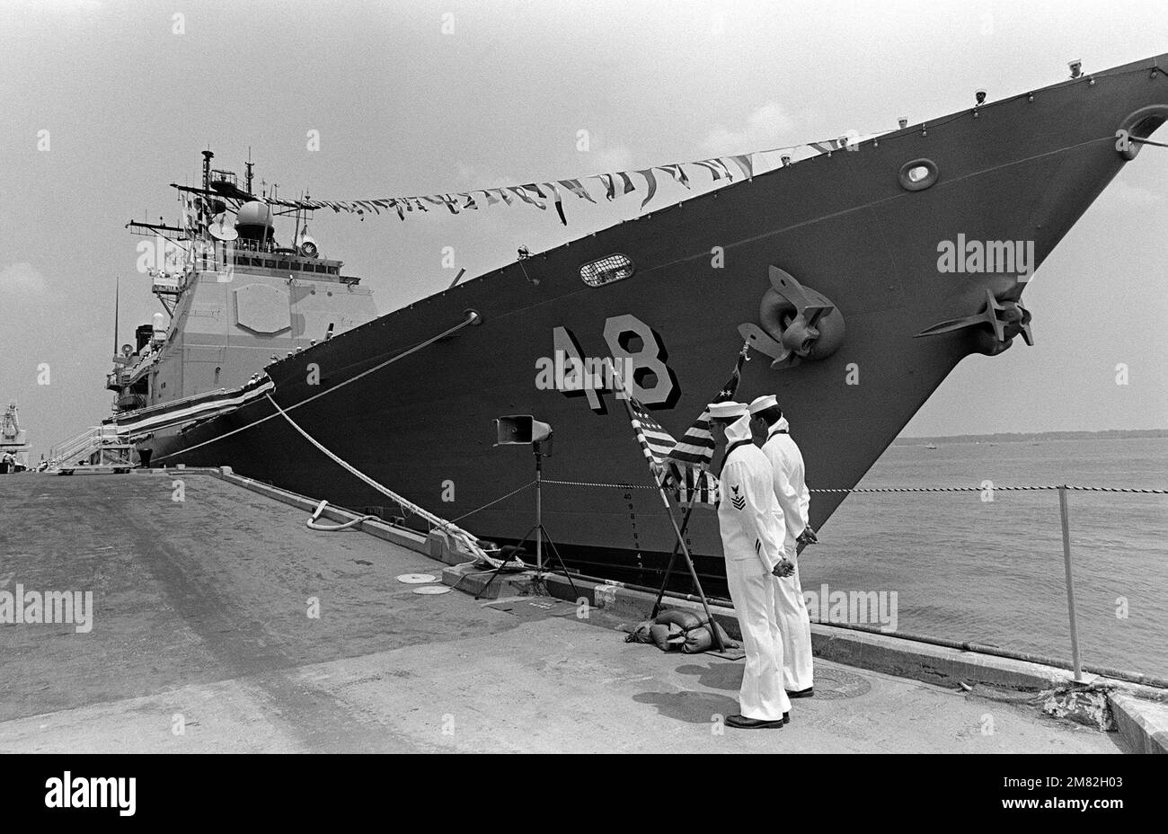 Two crewmen stand at parade rest near the bow of the Aegis guided ...