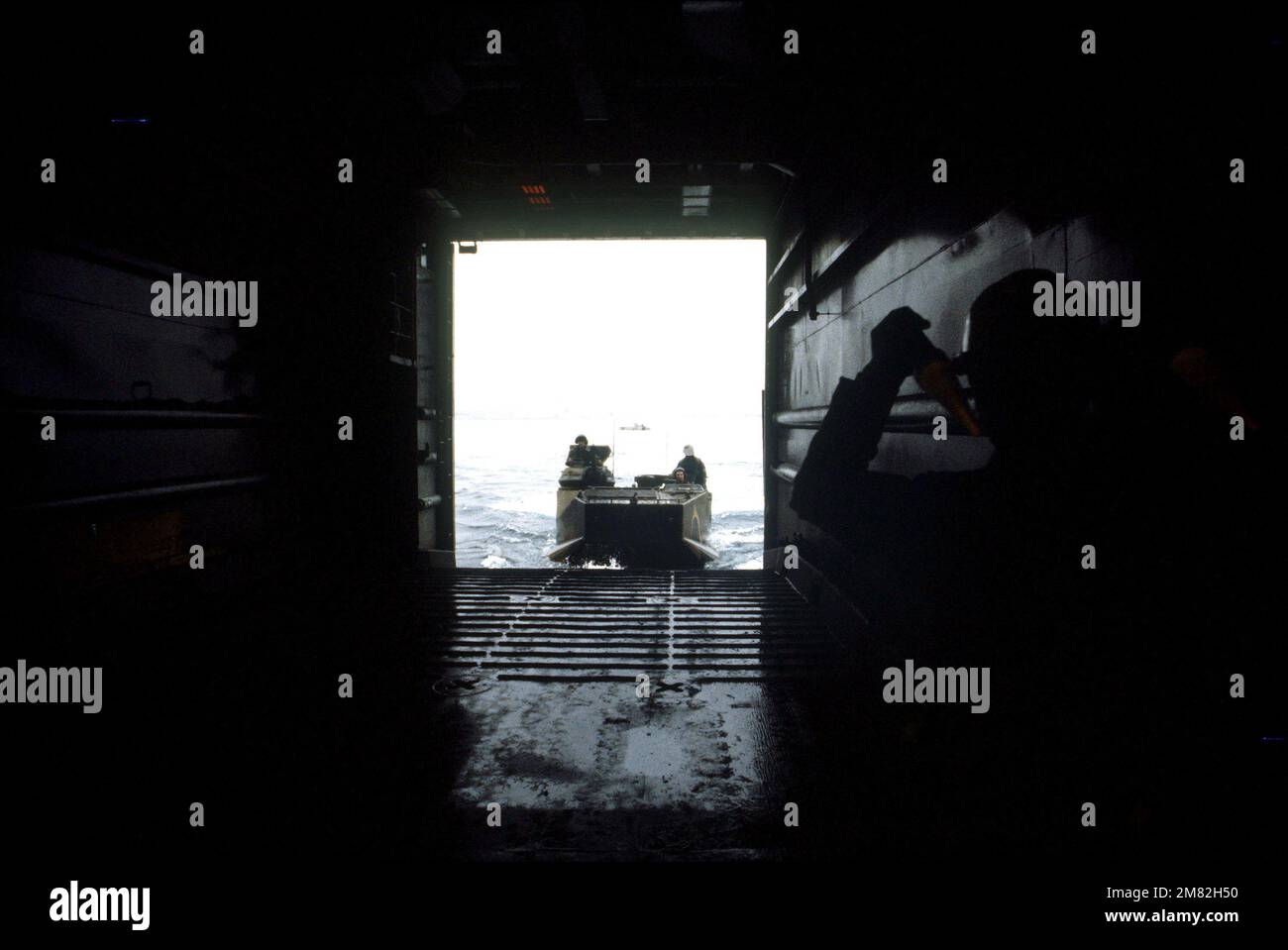 A salior with lighted wands guides an AAVP-7 amphibious assault vehicle ...