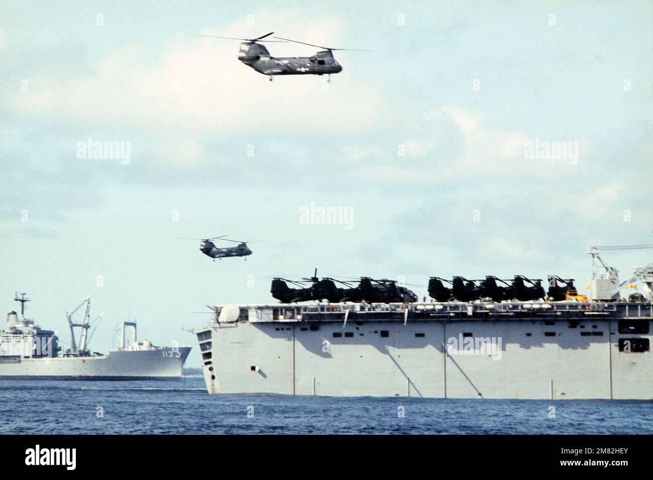 Two CH-46 Sea Knight helicopters fly above the amphibious cargo ship ...