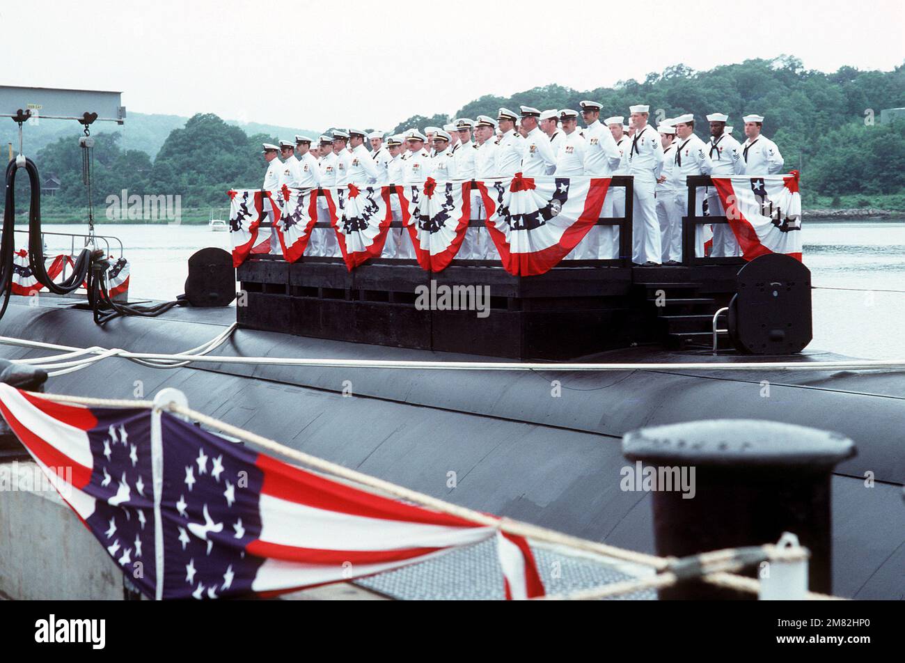 Crewmen stand in formation on the deck of the nuclear-powered attack ...