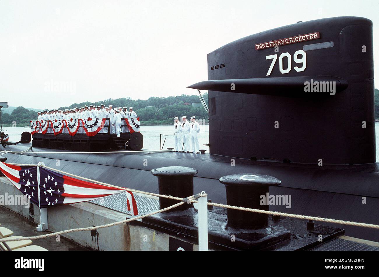 Crewmen stand in formation on the deck of the nuclear-powered attack ...