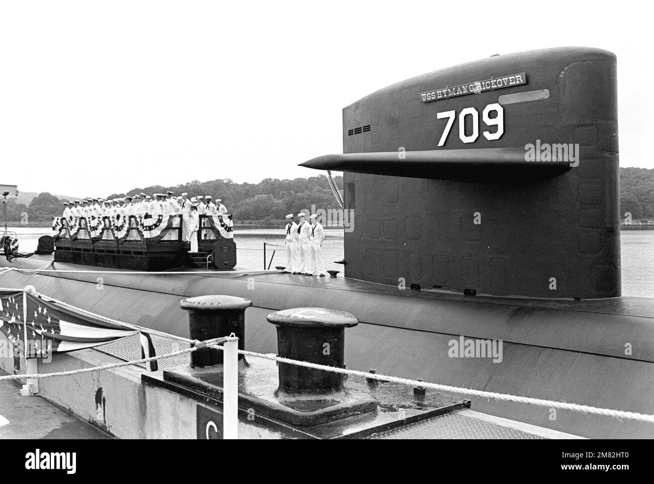 Crewmen stand in formation on the deck of the nuclear-powered attack ...