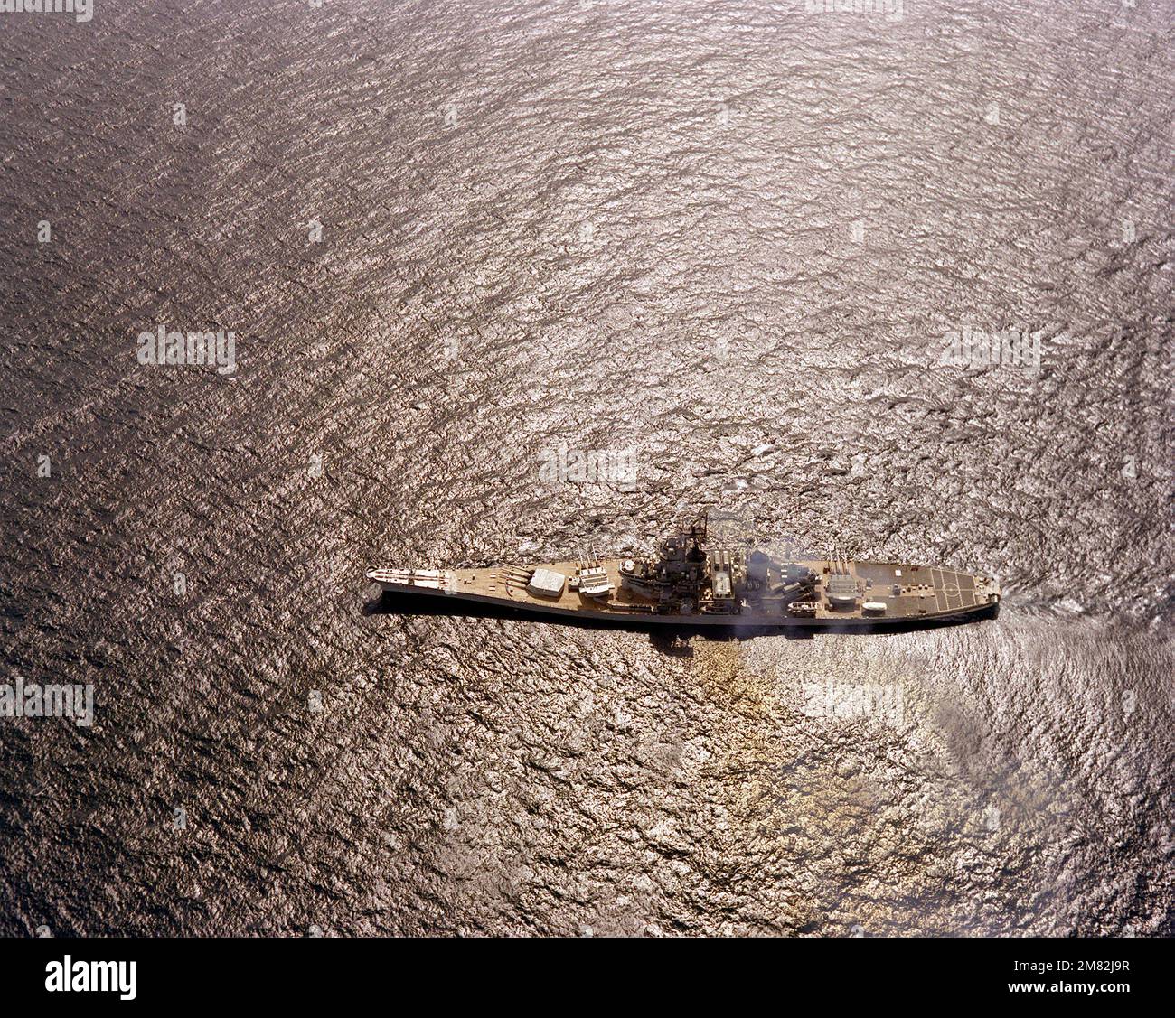 An elevated port beam view of the battleship USS IOWA (BB-61) as the ship's three Mark 7 16-inch ...