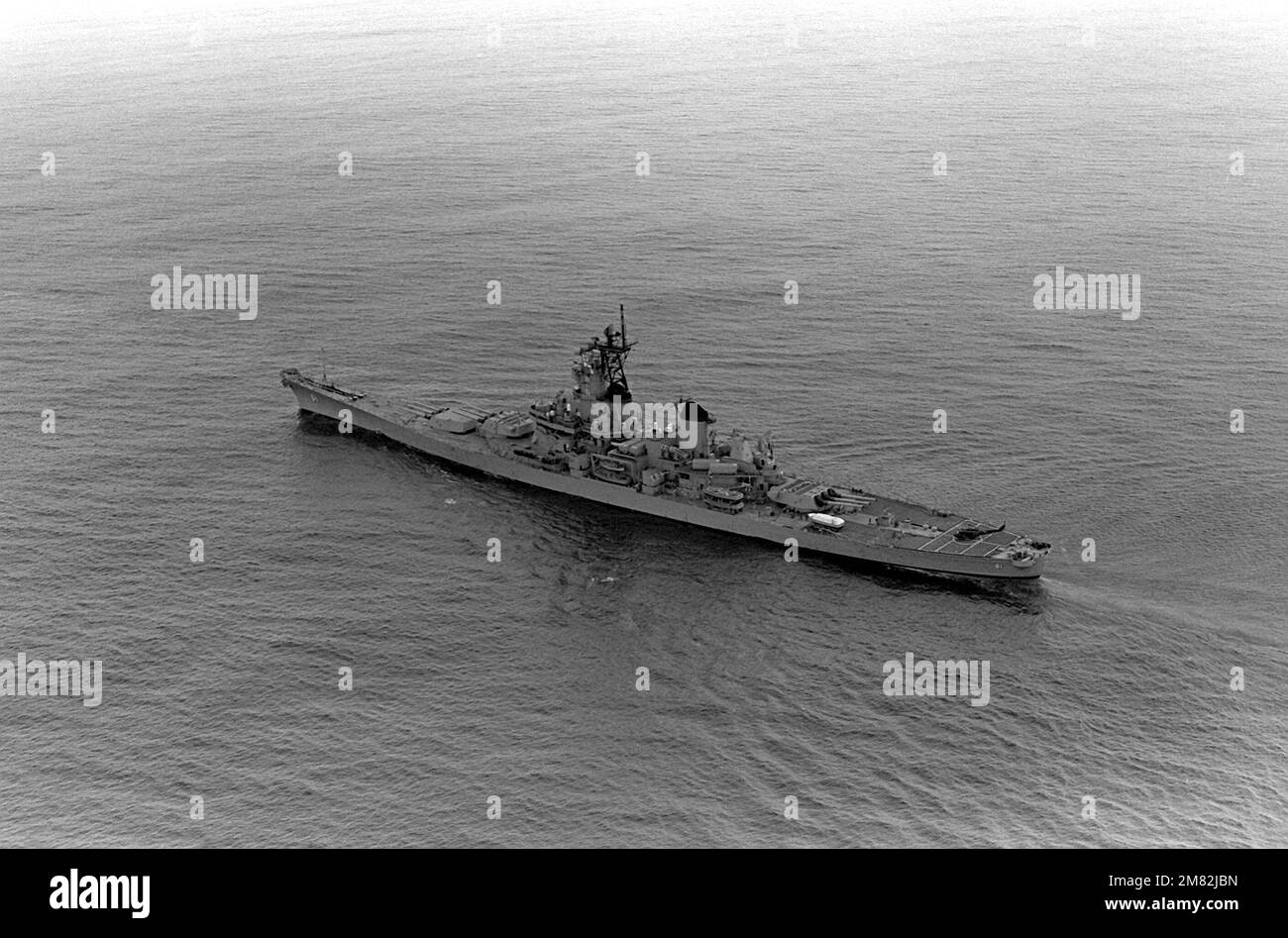 An elevated port quarter view of the battleship USS IOWA (BB-61) underway with a UH-1 Iroquois ...