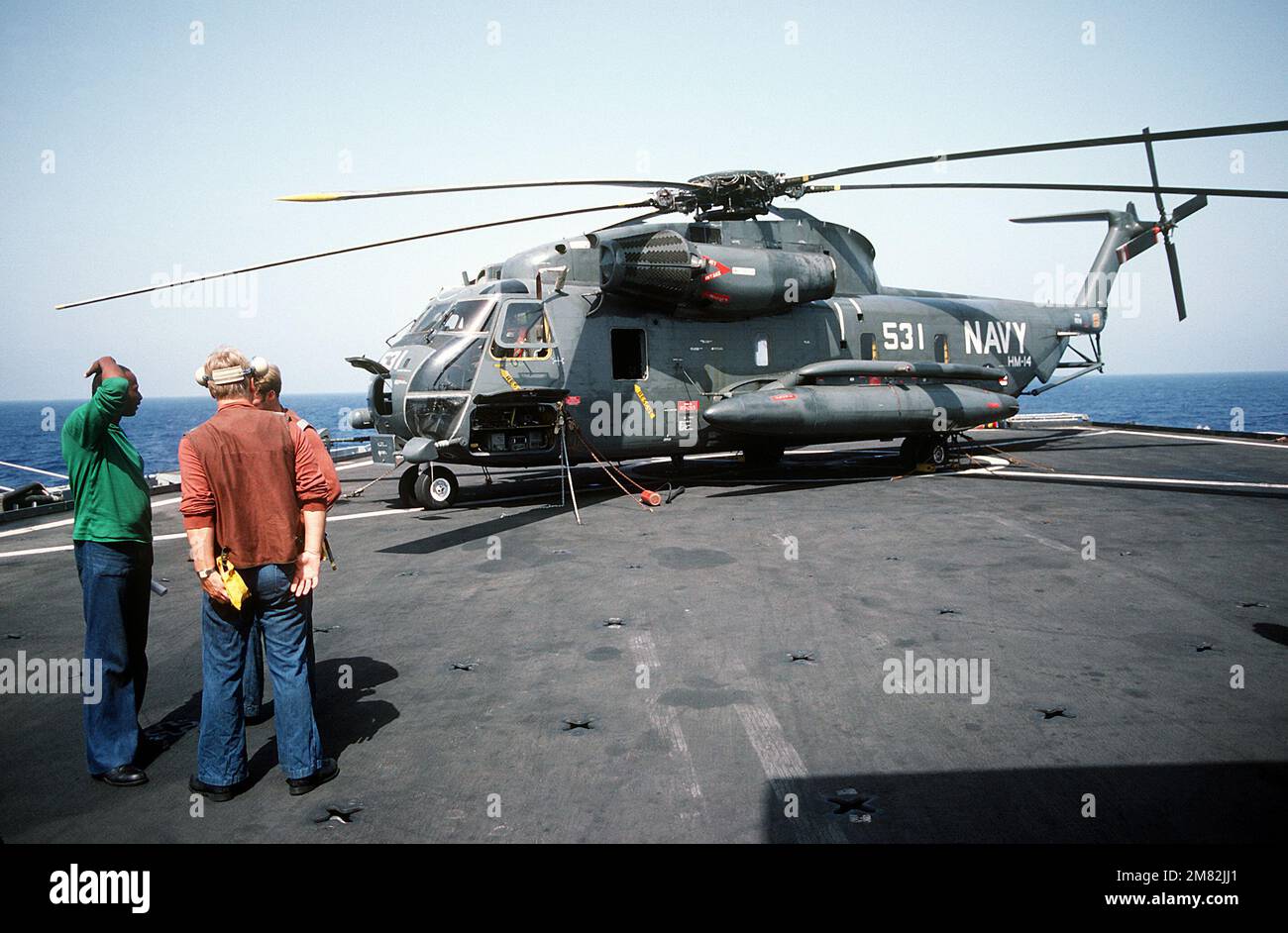 Flight deck crewmen stand by after an RH-53D Sea Stallion helicopter ...