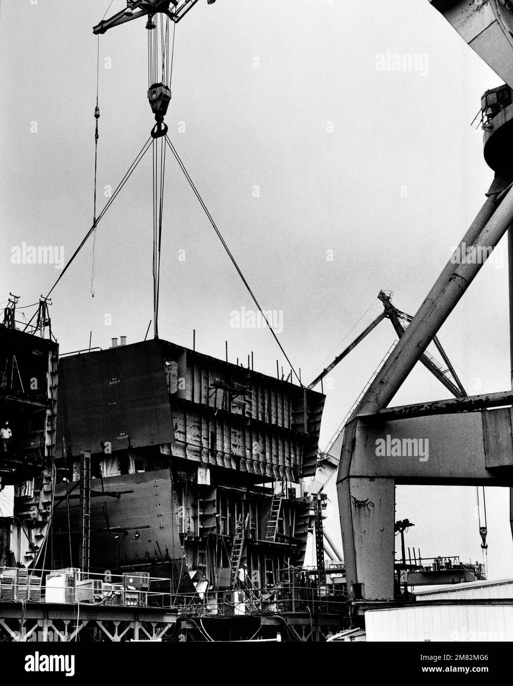 A heavy lift lowers a steel deck/bulkhead assembly into place on the ...