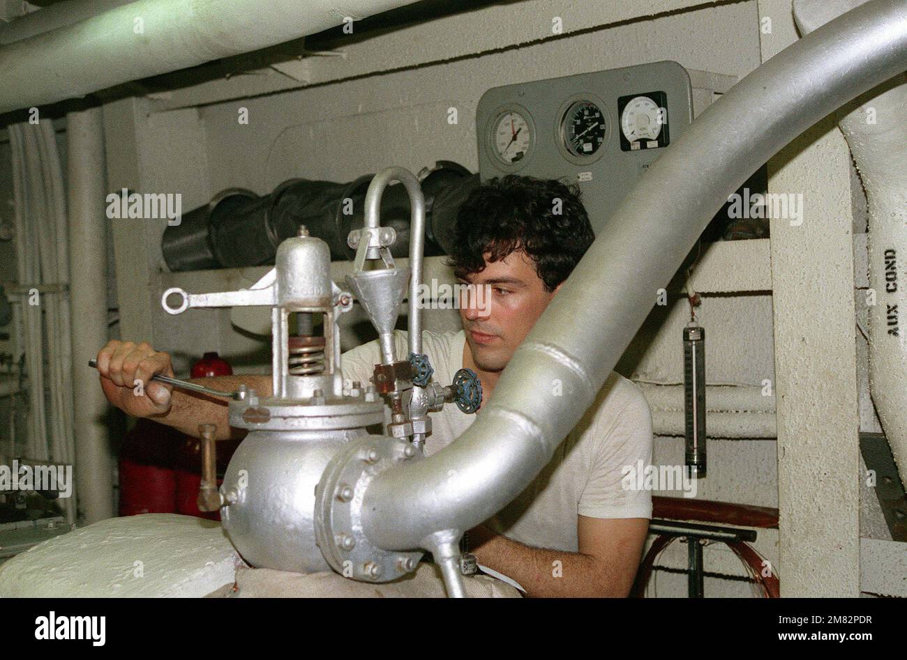 Machinist's Mate Fireman Howard S. Dugan works on a valve aboard the ...