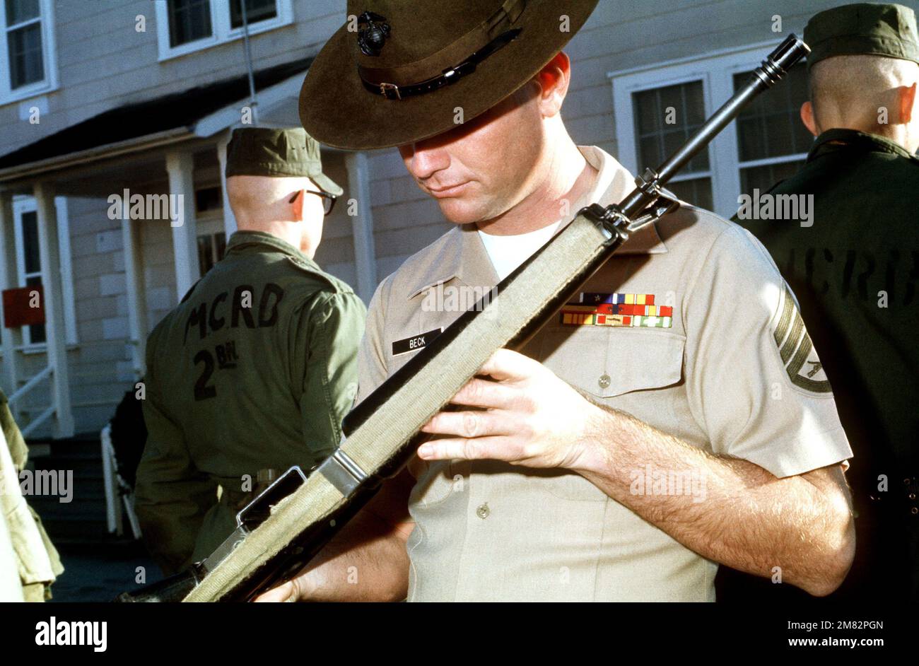 A Marine drill instructor inspects a recruit's M16A1 rifle during basic ...