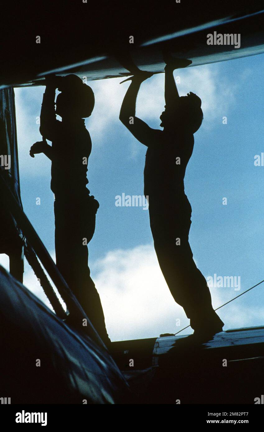 Two plane captains work on the underside of an EC-2 Hawkeye airborne ...