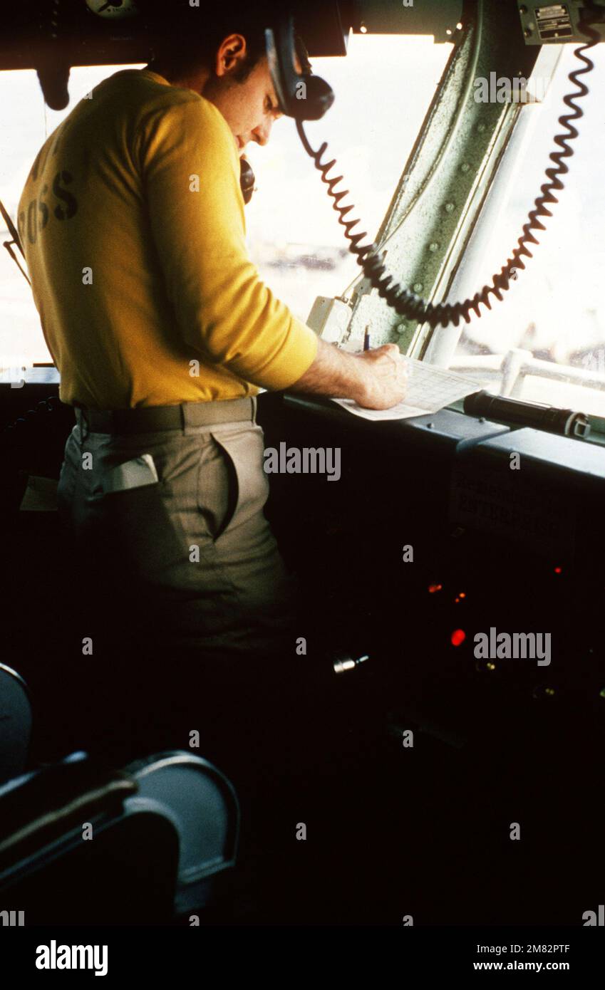 Commander Lawrence E. Gardiner, air boss, makes a note of changes to ...