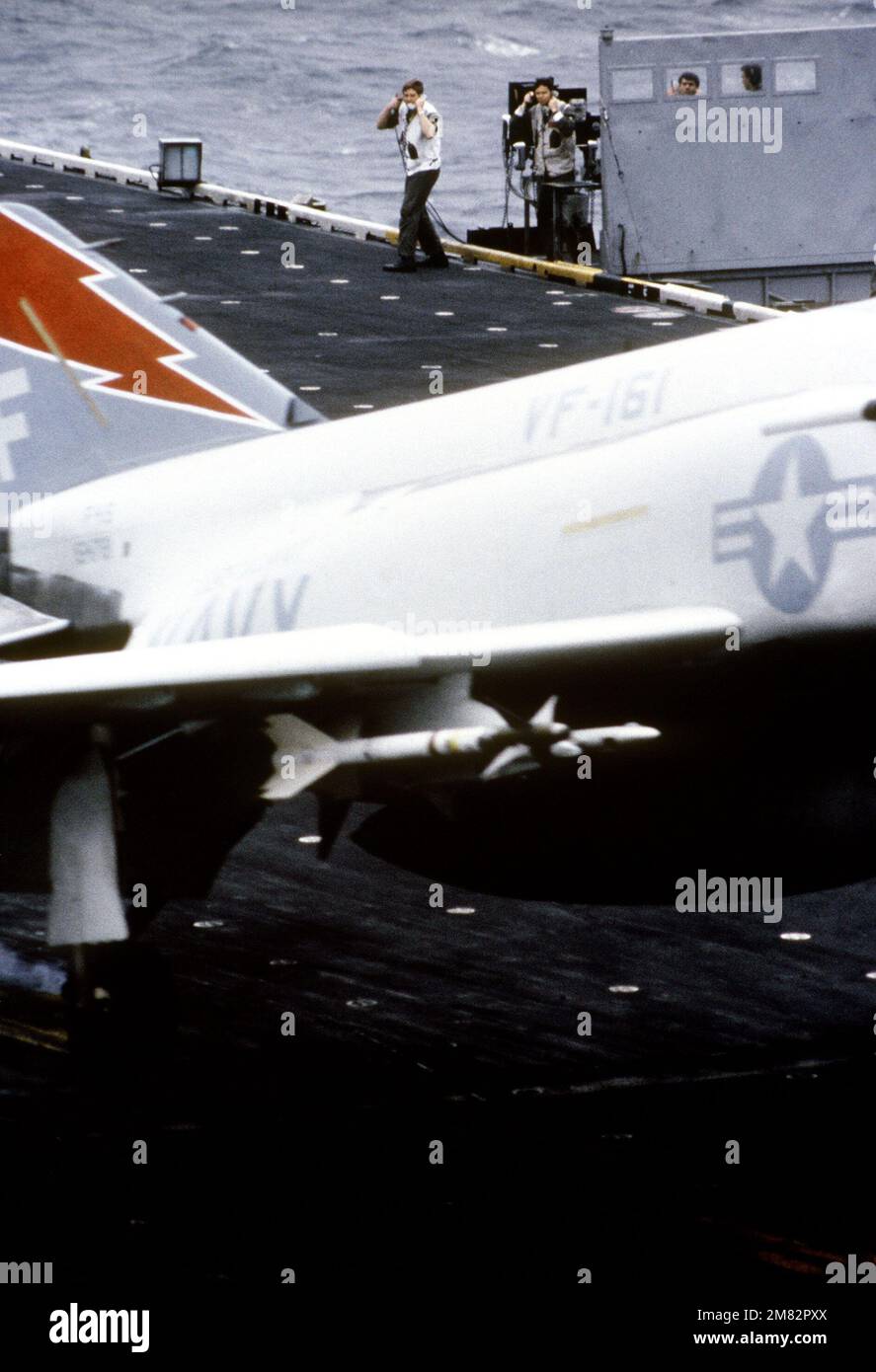 A landing signal officer (LSO) watches as an F-4S Phantom II aircraft ...