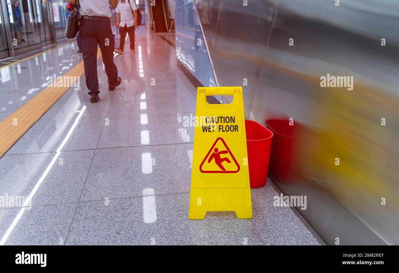 "Caution wet floor" sign in subway station Stock Photo - Alamy