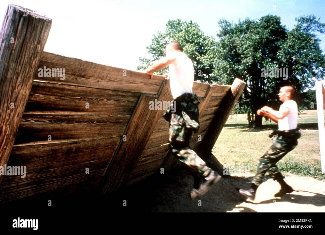 Recruits leap onto a wooden wall on the obstacle course during basic ...