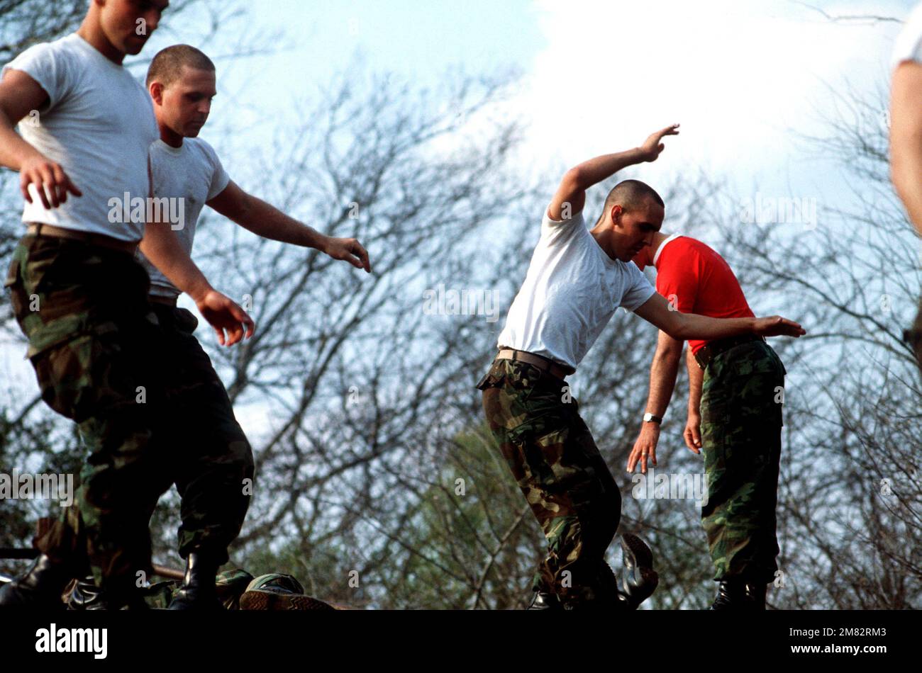 Recruits try to maintain their balance while crossing a log bridge on ...