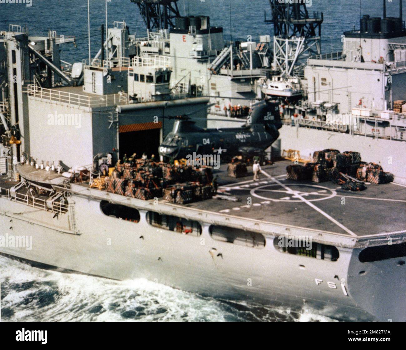 A CH-46 Sea Knight helicopter prepares to lift cargo from the deck of ...