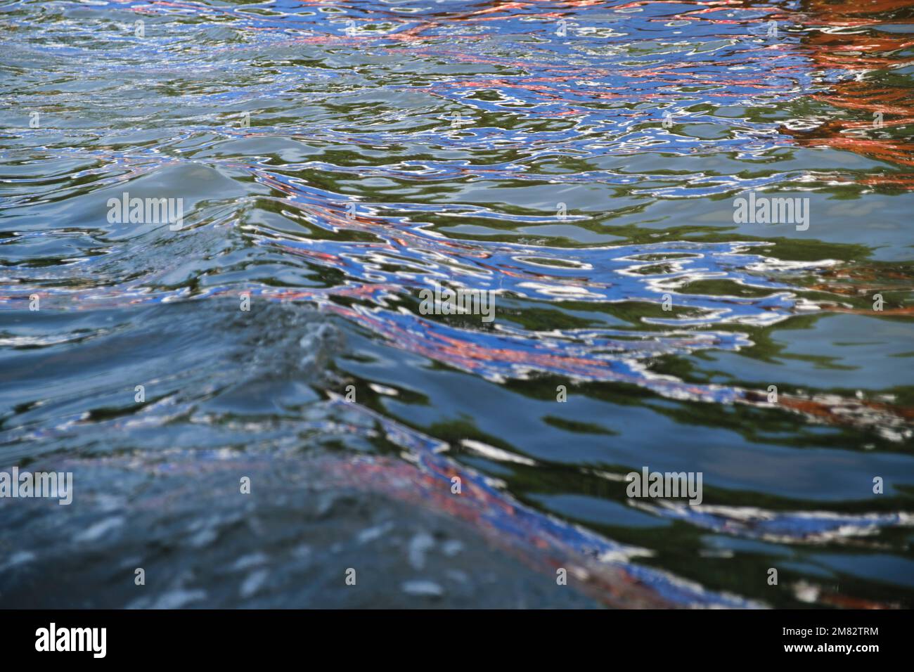 Reflections of colors on the surface of the water of a river, a blue ...