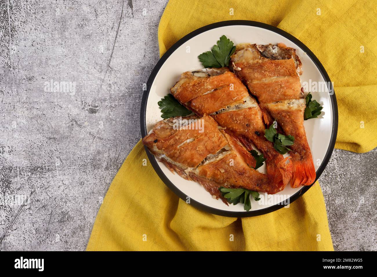 Pan Fried Rose fish with herbs on a round plate on a dark background ...