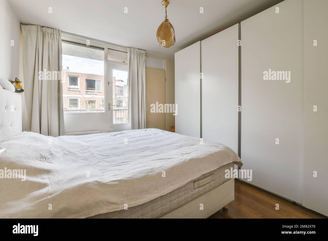 a bedroom with a bed and wardrobes on the wall, in front of a sliding ...