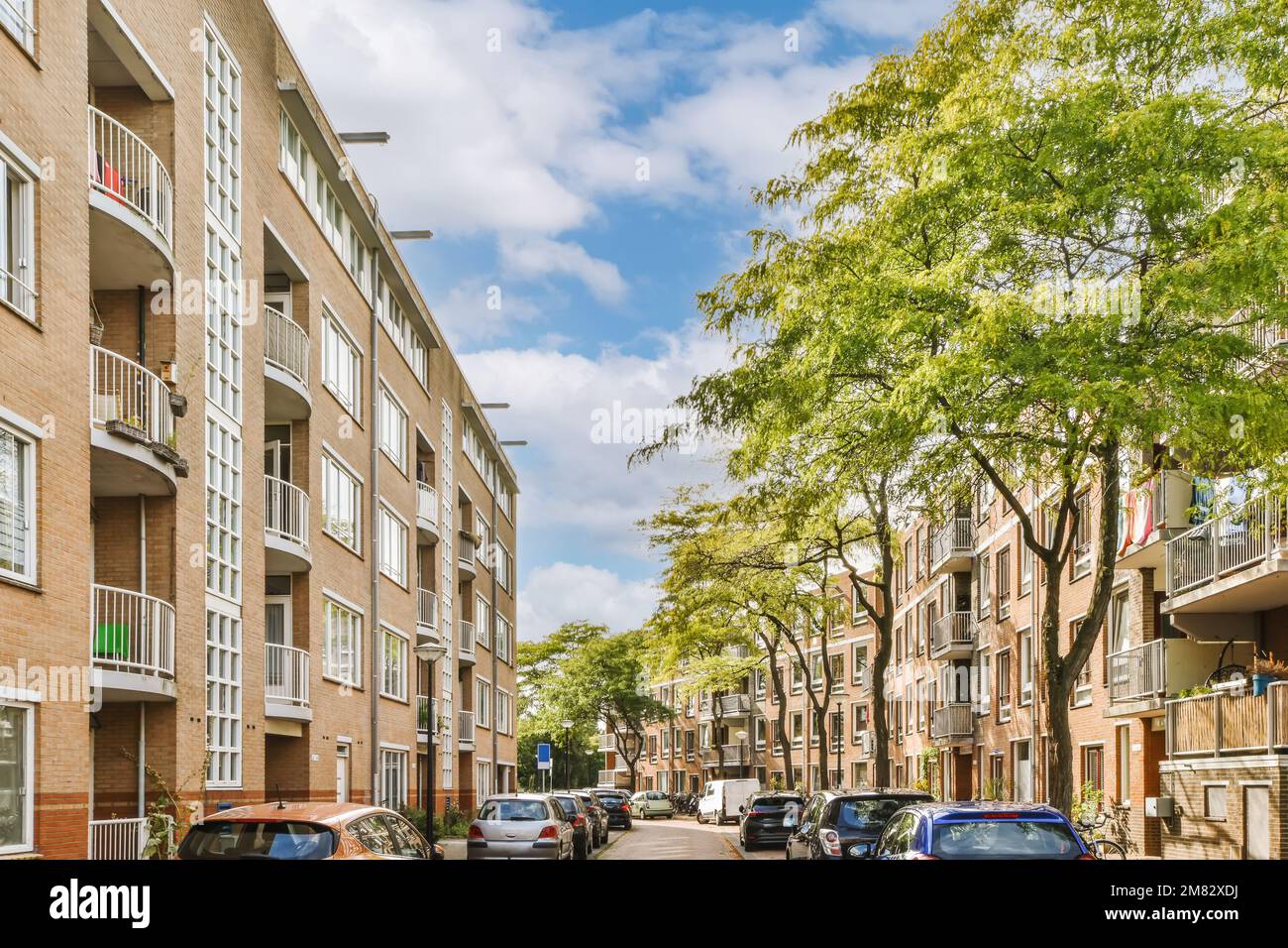 a street with cars parked on both sides and trees in the middle part of ...