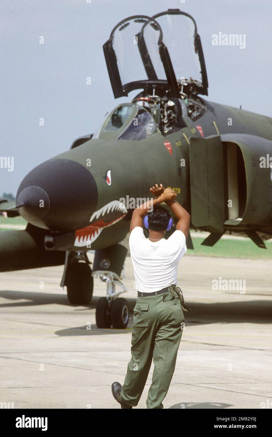 A ground crewman signals to a pilot aboard an F-4 Phantom II aircraft ...