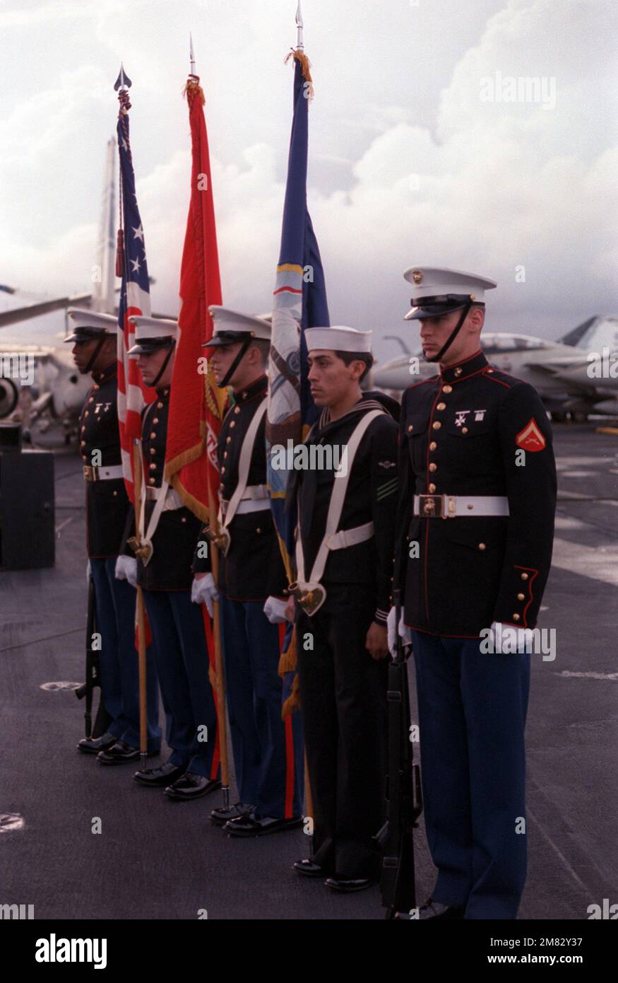 A Navy/Marine Corps color guard stands at attention during a memorial ...
