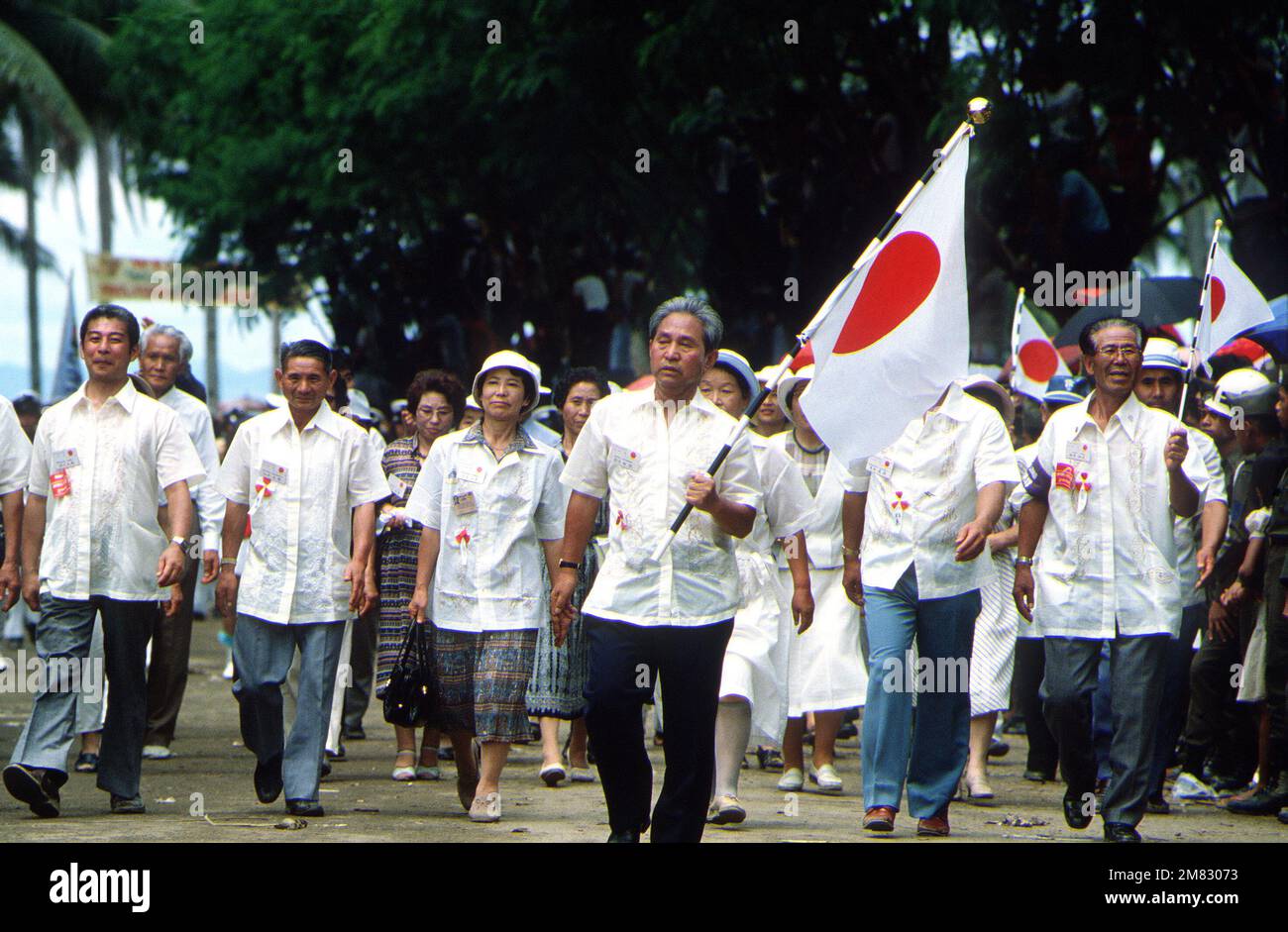 Members of a local organization, waving Japanese flags, march in a ...
