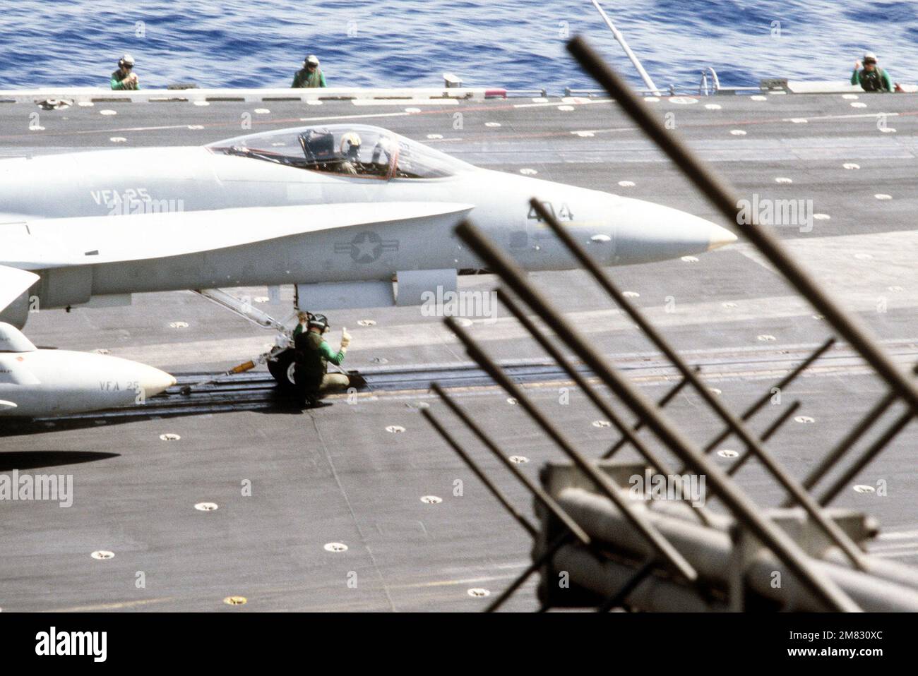 A catapult crewman checks the catapult connections on an F/A-18A Hornet ...