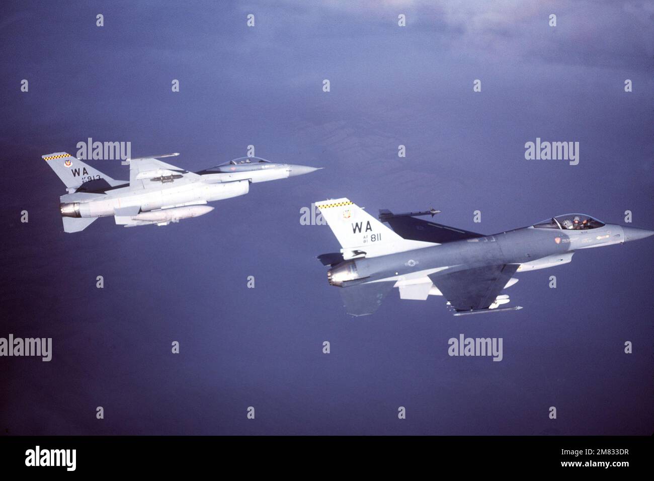 An air-to-air right side veiw of two F-16A Fighting Falcon aircraft ...