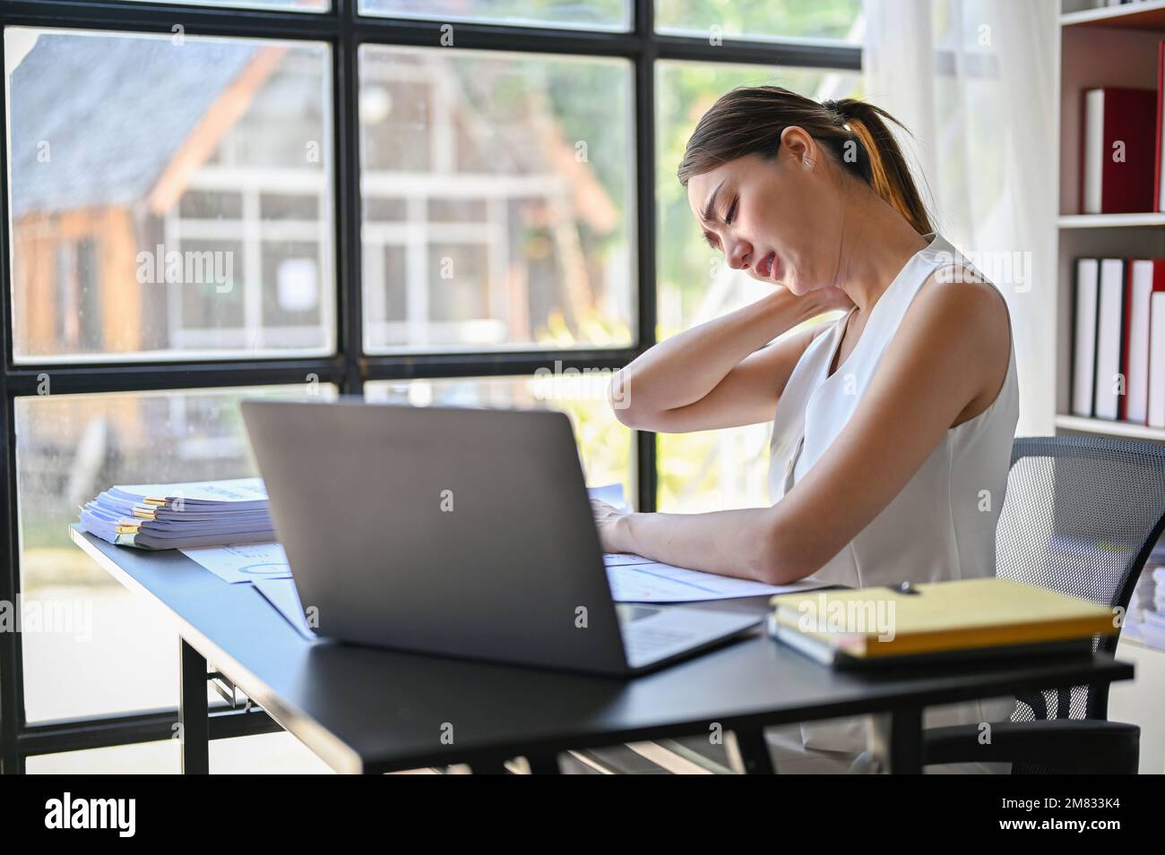 Tired and overworked millennial Asian businesswoman or female manager ...