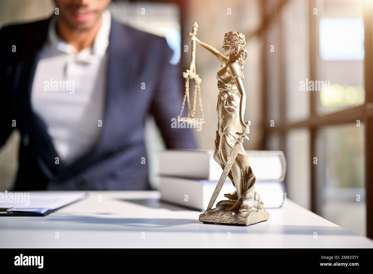The Statue of Justice or lady justice with scales of justice on a table over blurred background ...